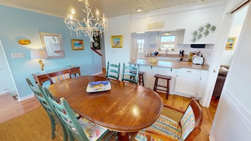 Uma sala de jantar com uma mesa de madeira, cadeiras e um candelabro.