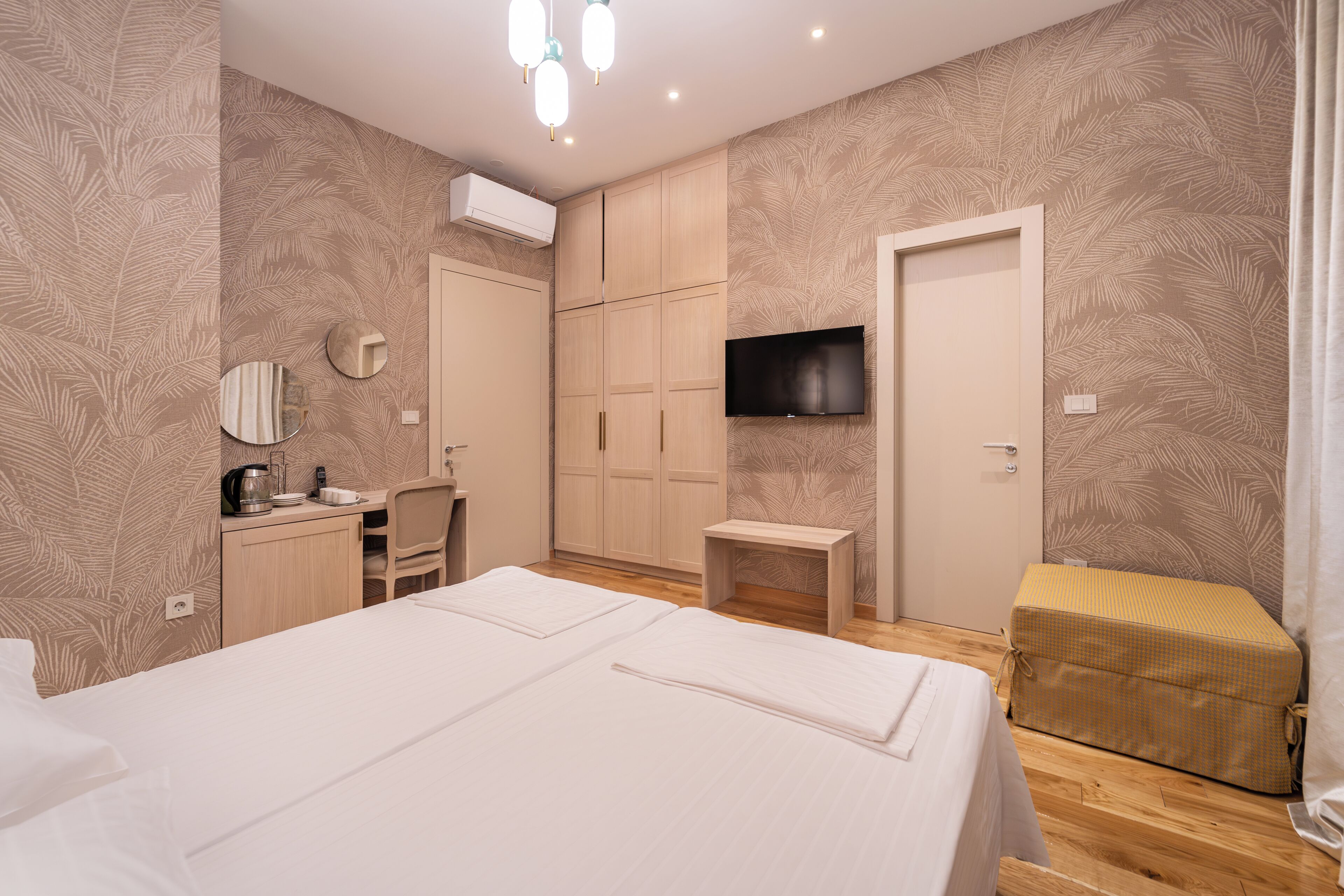 Quarto com cama, escrivaninha com cadeira, televisão na parede e armário.