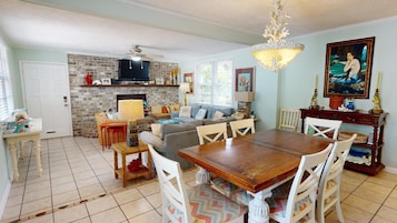 Uma sala de estar ampla com lareira, mesa de jantar e um confortável espaço de estar.