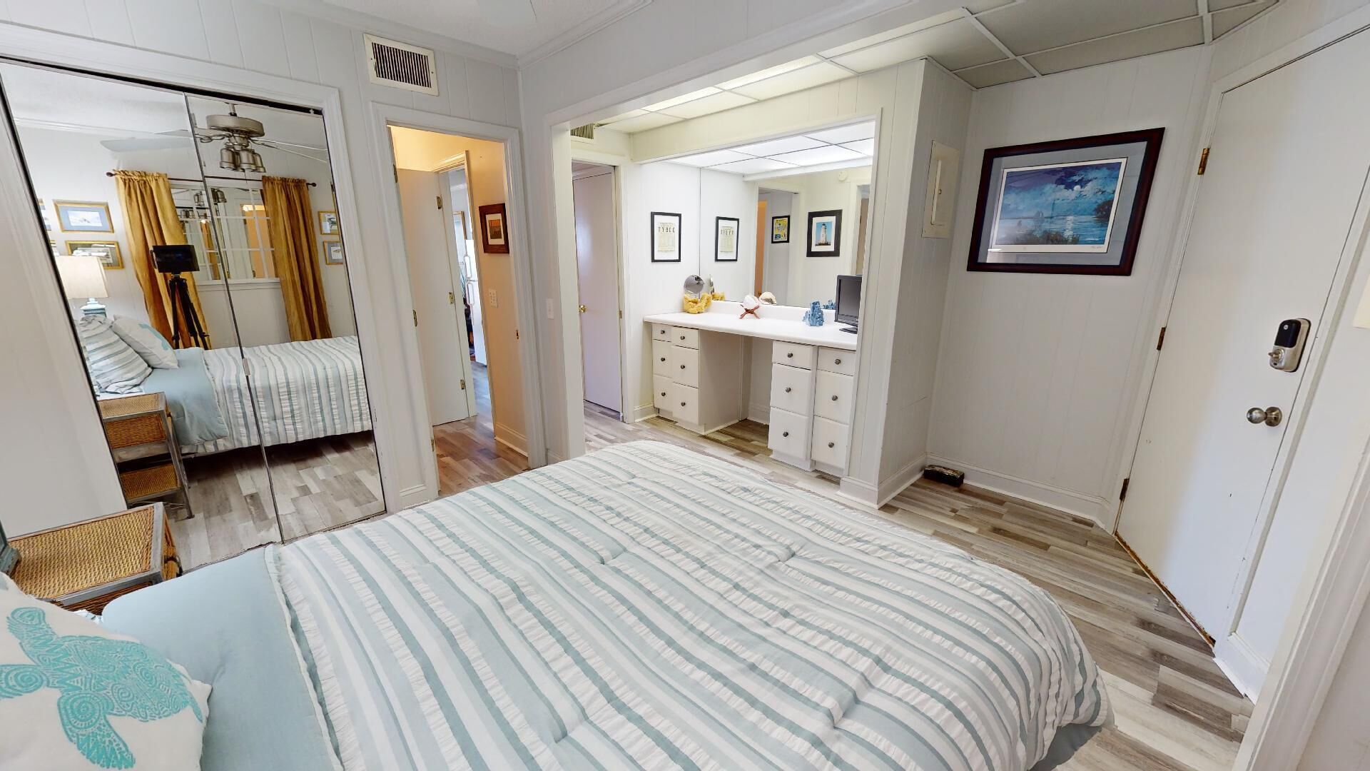 Quarto com cama, mesa de cabeceira, cômoda e espelho.