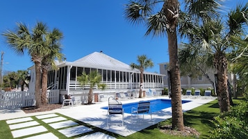 Uma casa com alpendre, piscina e palmeiras.