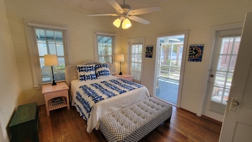 Quarto com cama, duas mesas de cabeceira, ventilador de teto e uma janela.