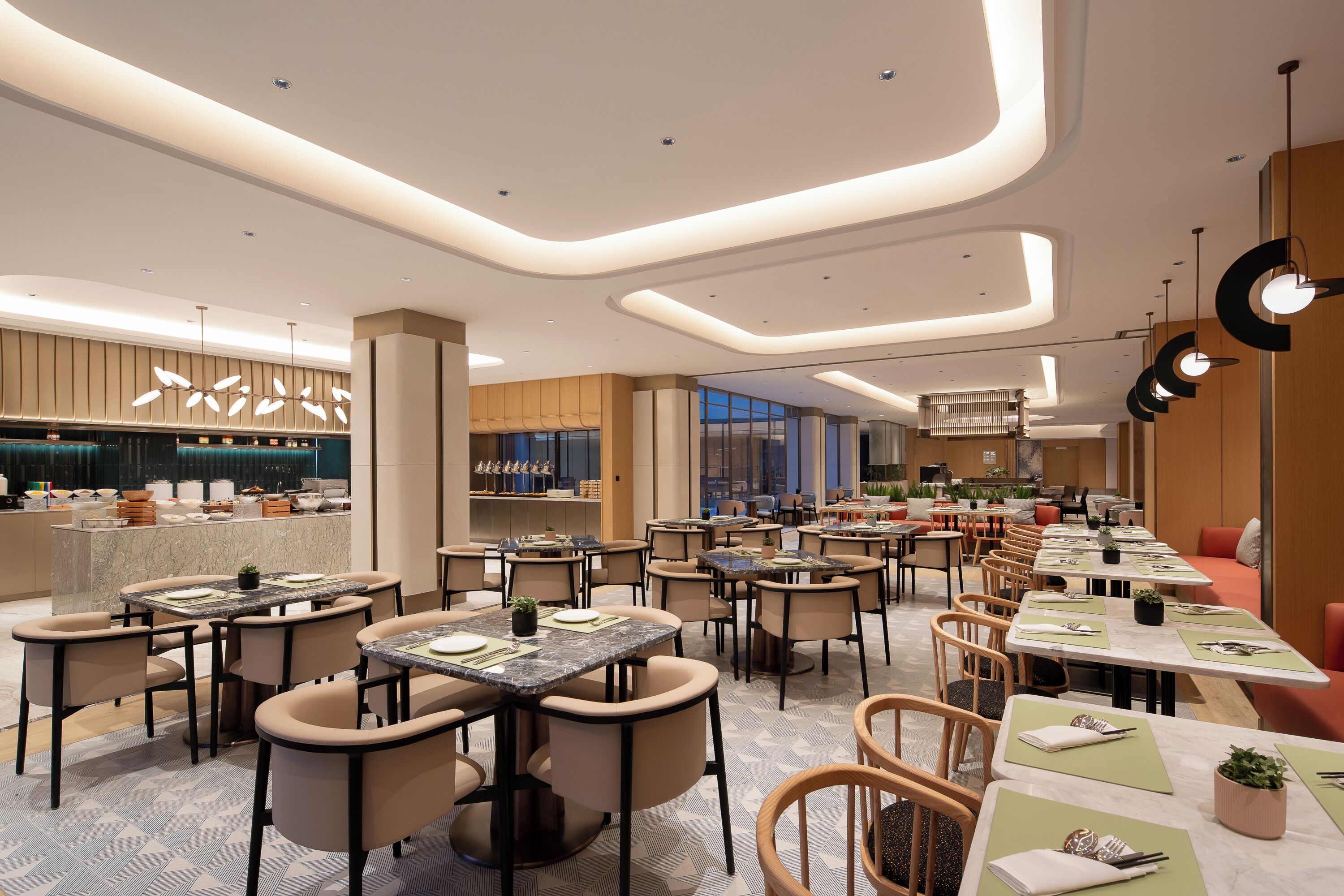 Um restaurante moderno com várias mesas e cadeiras, uma área de cozinha e um bar.