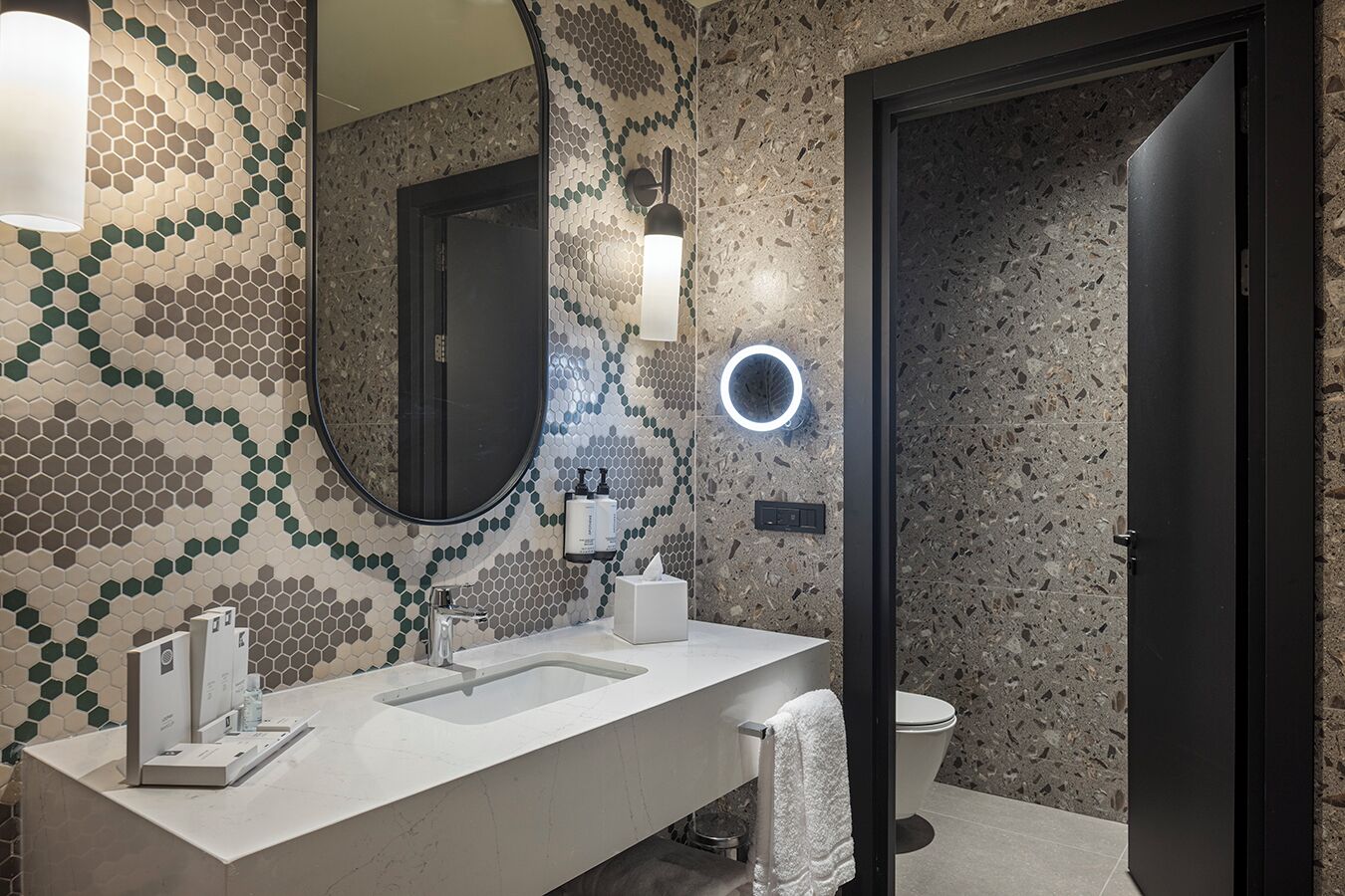 Uma casa de banho moderna com um espelho grande, duas pias, uma sanita e uma porta.
