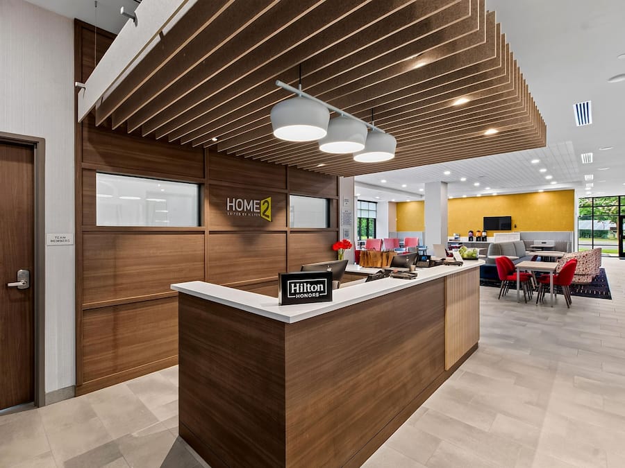 Uma área de recepção de hotel com um balcão de madeira, sinalização 'Hilton Honors' e design de interiores moderno.
