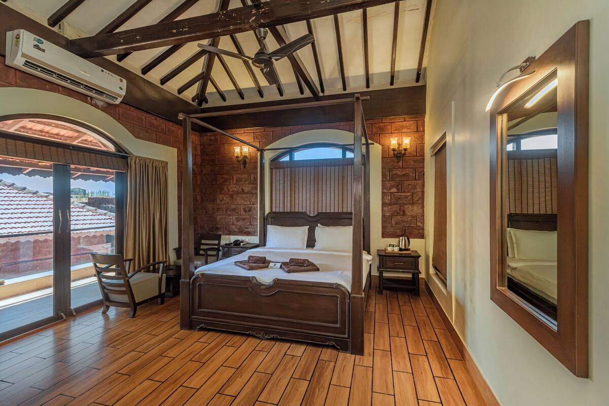 Quarto espaçoso com cama grande, piso de madeira e vista para o exterior.