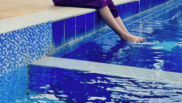 Uma pessoa sentada na borda da piscina.