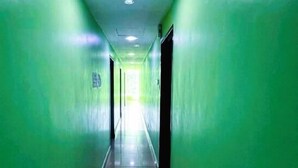 Um corredor comprido e estreito, com paredes verdes e chão de azulejos.