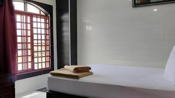 Quarto de hotel com uma cama, janela com vista e uma obra de arte pendurada na parede.