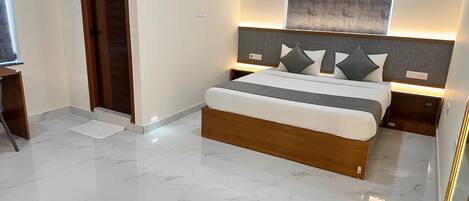 Quarto moderno com uma cama grande, piso de mármore e porta de madeira.