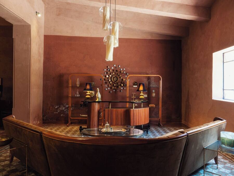 Um quarto aconchegante em estilo vintage, com um balcão de madeira curvo, uma mesa de jantar redonda e um sofá confortável.
