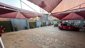 Um pátio pavimentado com piso de pedra em padrão, cercado por paredes e coberto por toldos vermelhos.