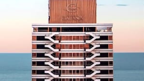 Hotel moderno com fachada de madeira e várias varandas, com vista para um corpo de água.
