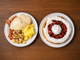 Duas porções de comida de café da manhã sobre uma mesa de madeira.