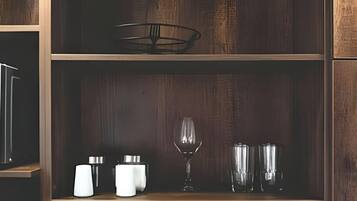 Uma prateleira de madeira com uma taça de vinho, dois copos e três recipientes para condimentos.
