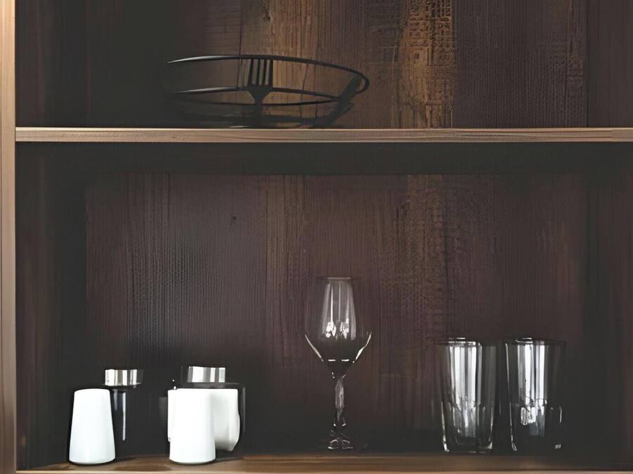 Uma prateleira de madeira com uma taça de vinho, dois copos e três recipientes para condimentos.