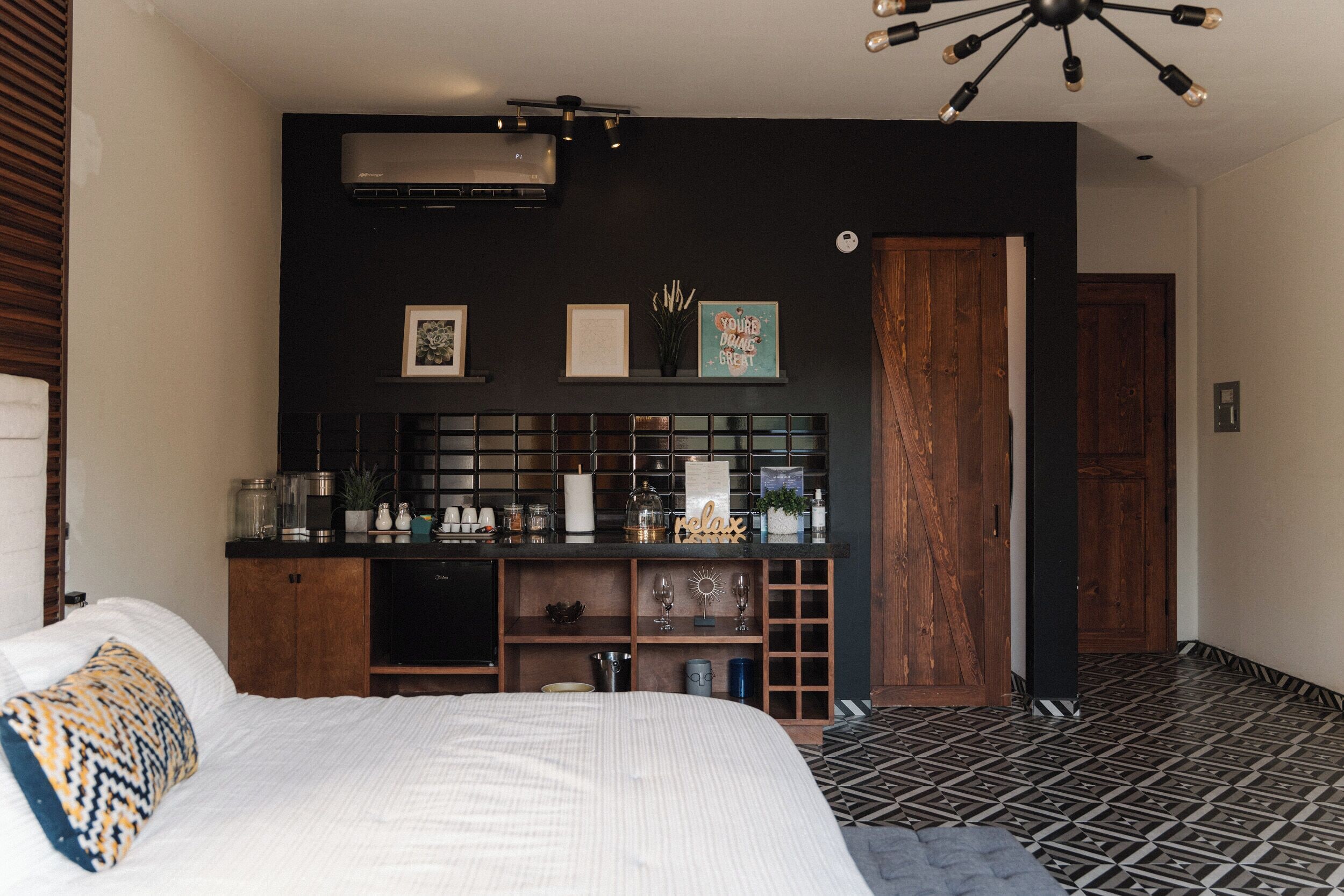 Quarto moderno com cama, escrivaninha embutida e piso estampado em preto e branco.