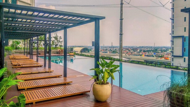 Uma área de piscina no terraço com espreguiçadeiras de madeira e um vaso de planta.