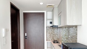 Uma cozinha moderna com porta de madeira, armários brancos, painel de azulejos e geladeira preta.
