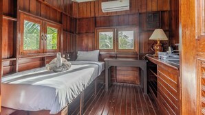 Quarto de cabana de madeira com duas camas, uma mesa e um aparelho de ar condicionado.