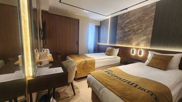 Quarto de hotel com escrivaninha, duas camas, um espelho grande e parede de mármore.