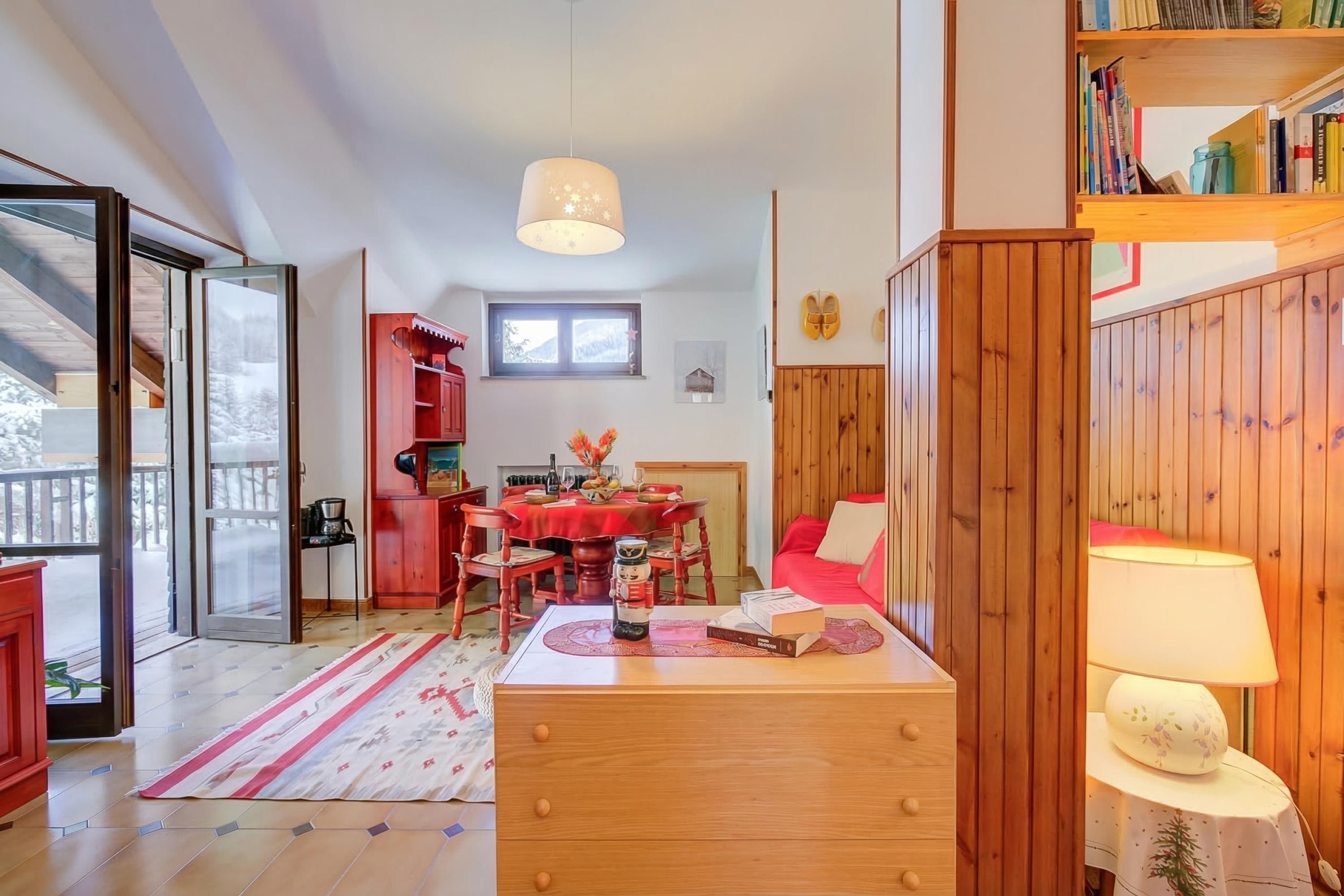 Uma sala de estar aconchegante com área de jantar, estante de madeira e uma janela grande.