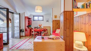 Uma sala de estar aconchegante com área de jantar, estante de madeira e uma janela grande.
