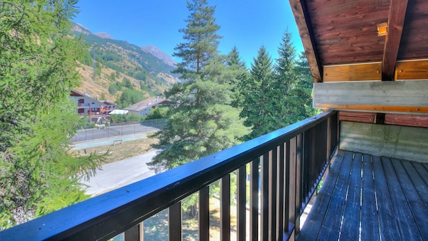 Um deck de madeira com vista para uma paisagem montanhosa e uma estrada.
