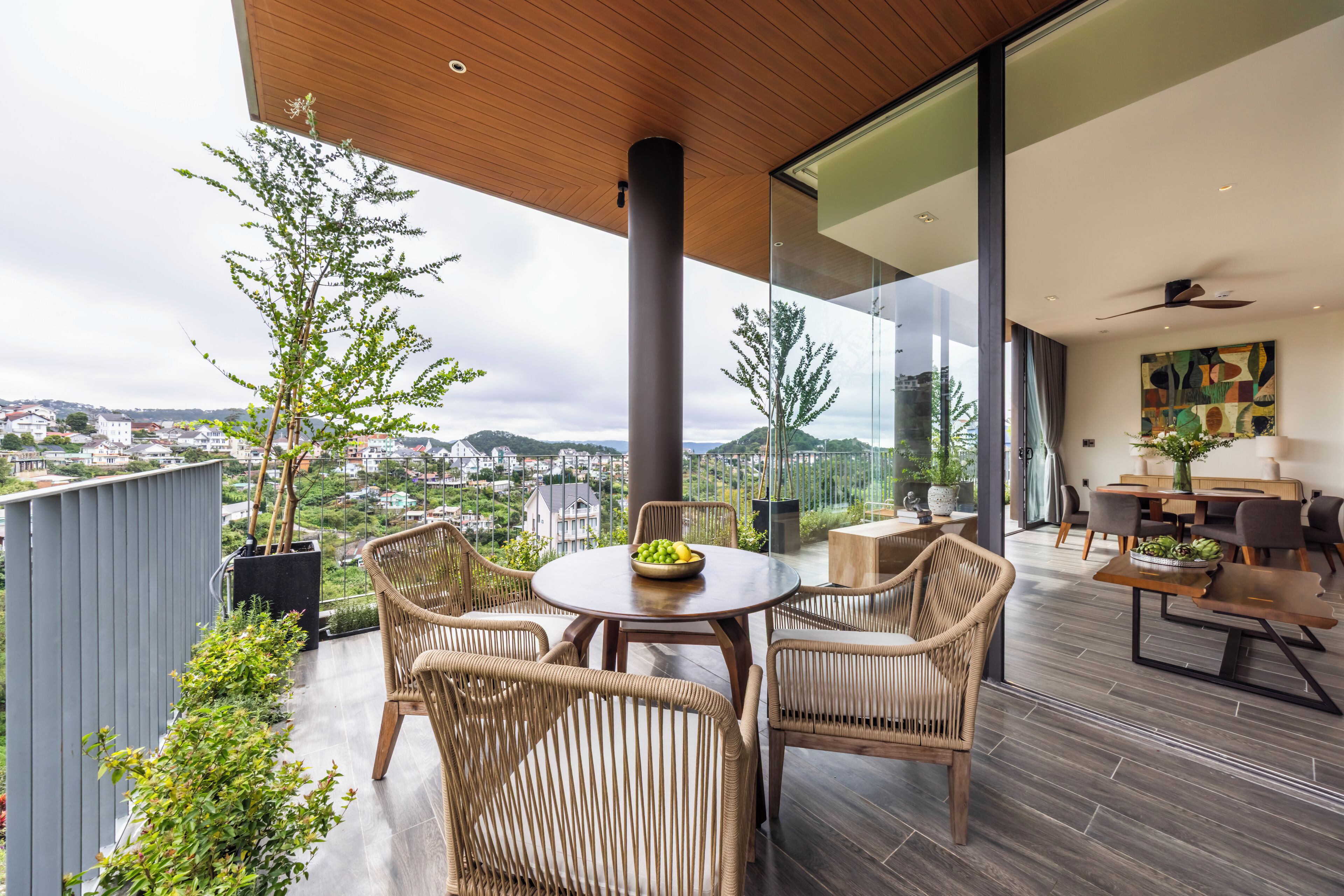 Uma área de refeições moderna ao ar livre com mobiliário de vime e vista para a cidade.