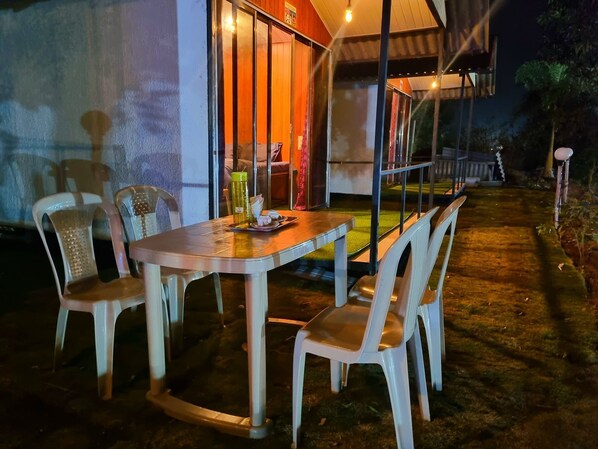 Uma área de refeições ao ar livre com mesa, cadeiras, uma garrafa de água e um cardápio.