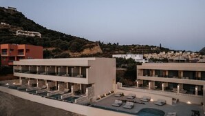 Um hotel moderno com vários andares, piscinas ao ar livre e vista para uma paisagem montanhosa.