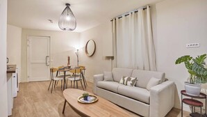 Um espaço de estar compacto com sofá, mesa de jantar e luminária pendente.