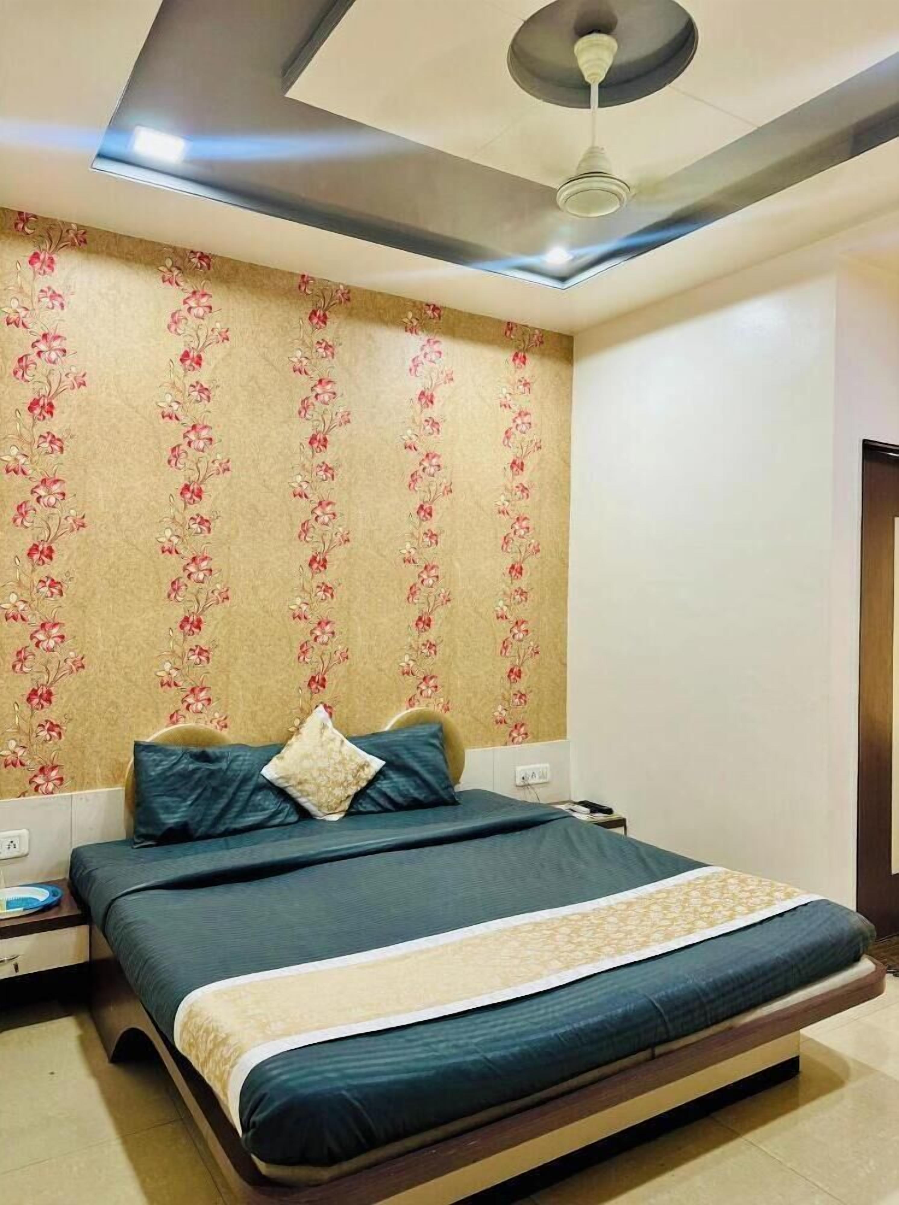 Quarto com cama, ventoinha no teto e papel de parede floral.