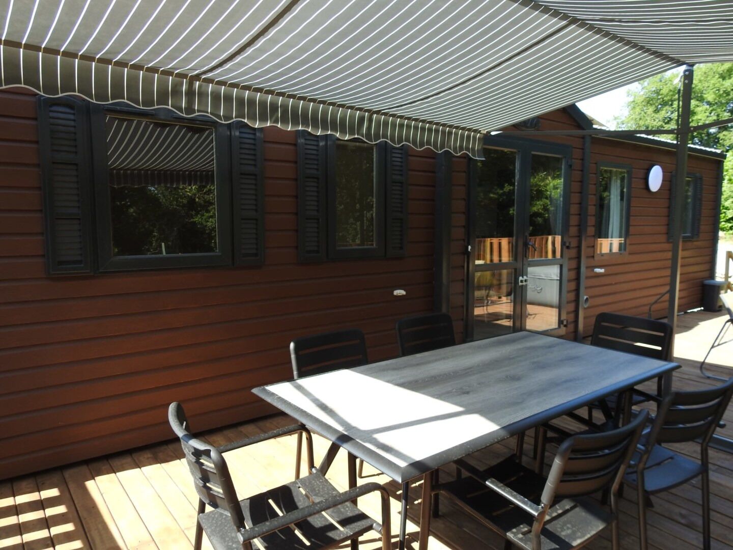 Uma cabana de madeira com varanda coberta, uma mesa e cadeiras.
