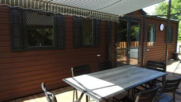 Uma cabana de madeira com varanda coberta, uma mesa e cadeiras.