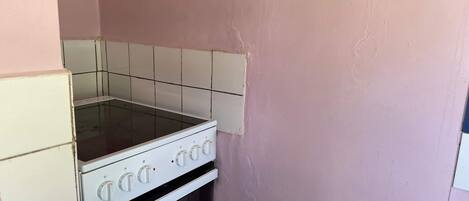 Uma cozinha pequena com fogão e forno brancos, e painel de azulejos.