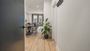 Cozinha moderna com piso de madeira, área de jantar com cadeiras e uma mesa, e uma janela grande com cortinas.