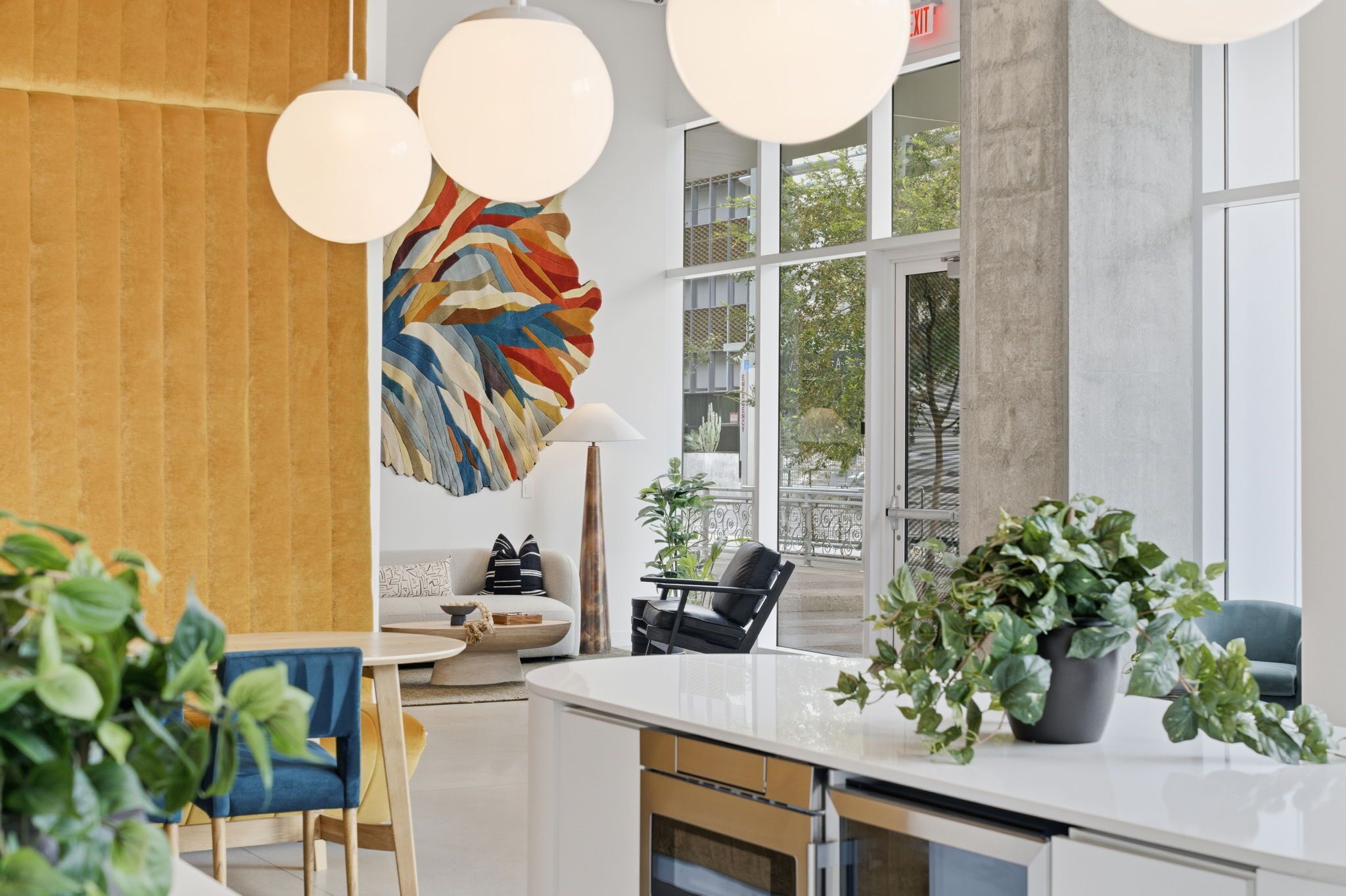 Um interior moderno com sofá, mesa de jantar, plantas em vasos e um grande quadro abstrato.