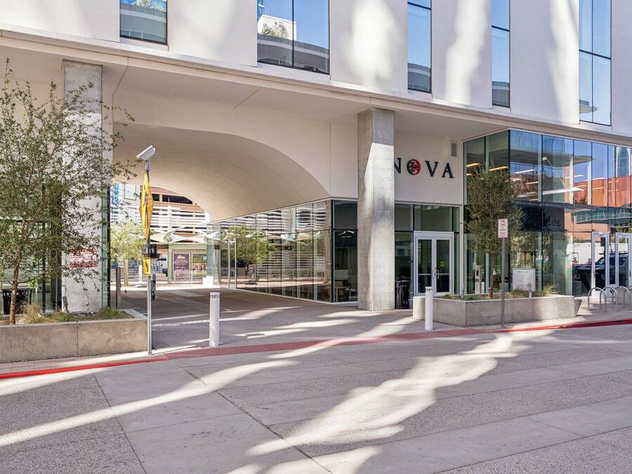 Um edifício moderno com entrada de vidro, logotipo visível e céu claro.
