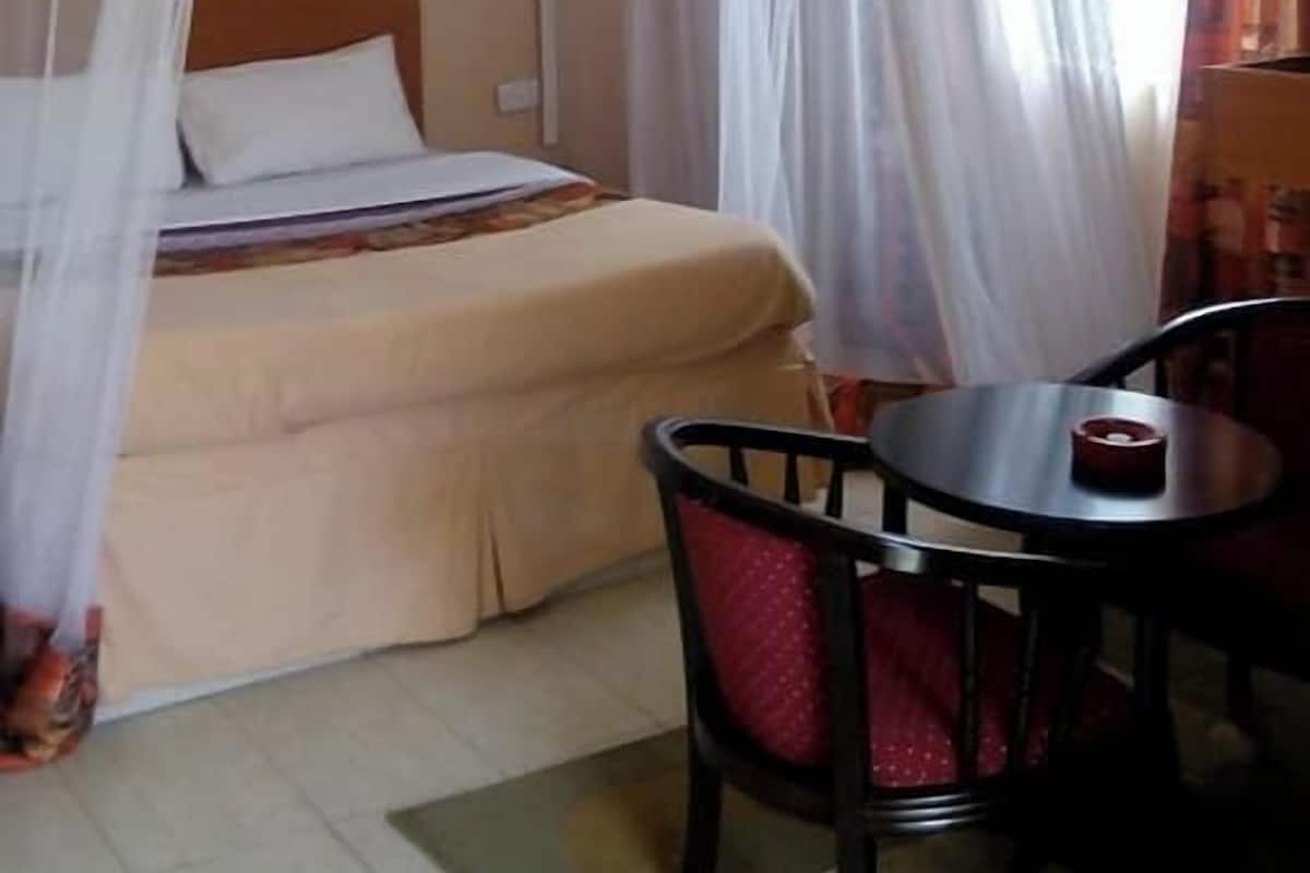 Quarto de hotel com uma cama, uma mesa e uma cadeira.