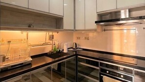 Uma cozinha moderna com eletrodomésticos de aço inoxidável, máquina de lavar louça e forno embutido.