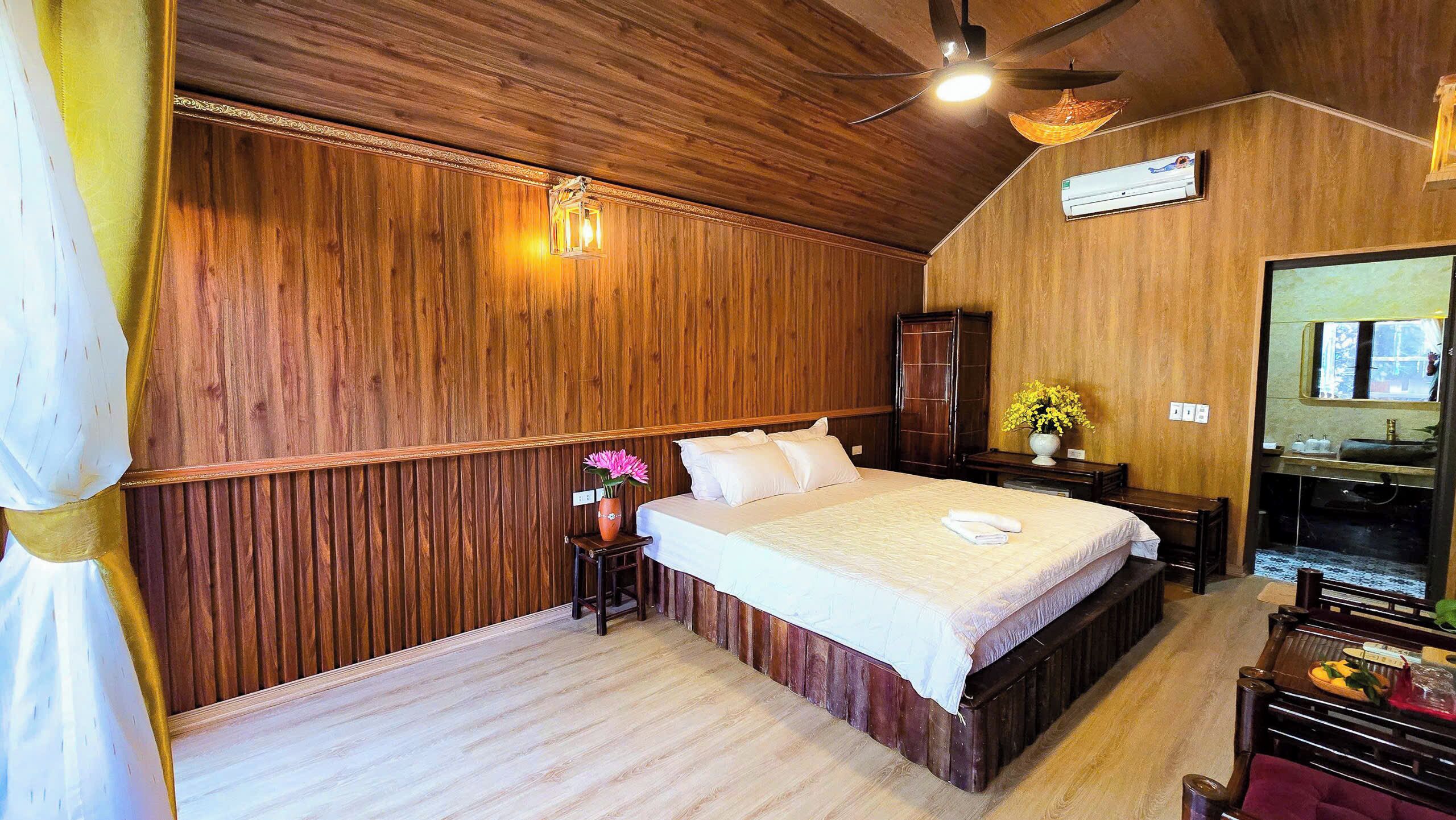 Quarto com painéis de madeira, uma cama, mesa de cabeceira e um espelho.