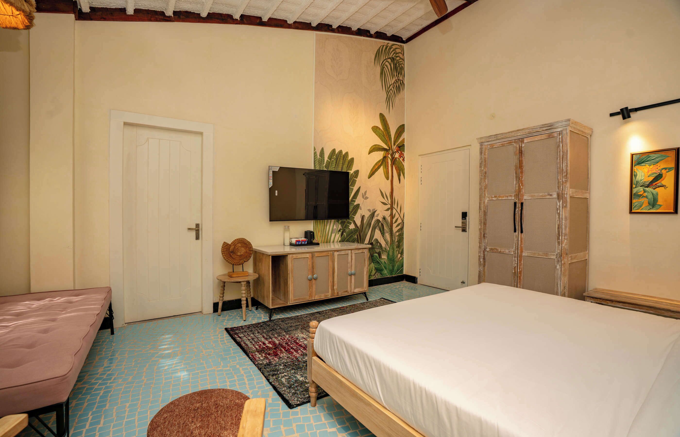 Quarto com cama, televisão, guarda-roupa e porta.