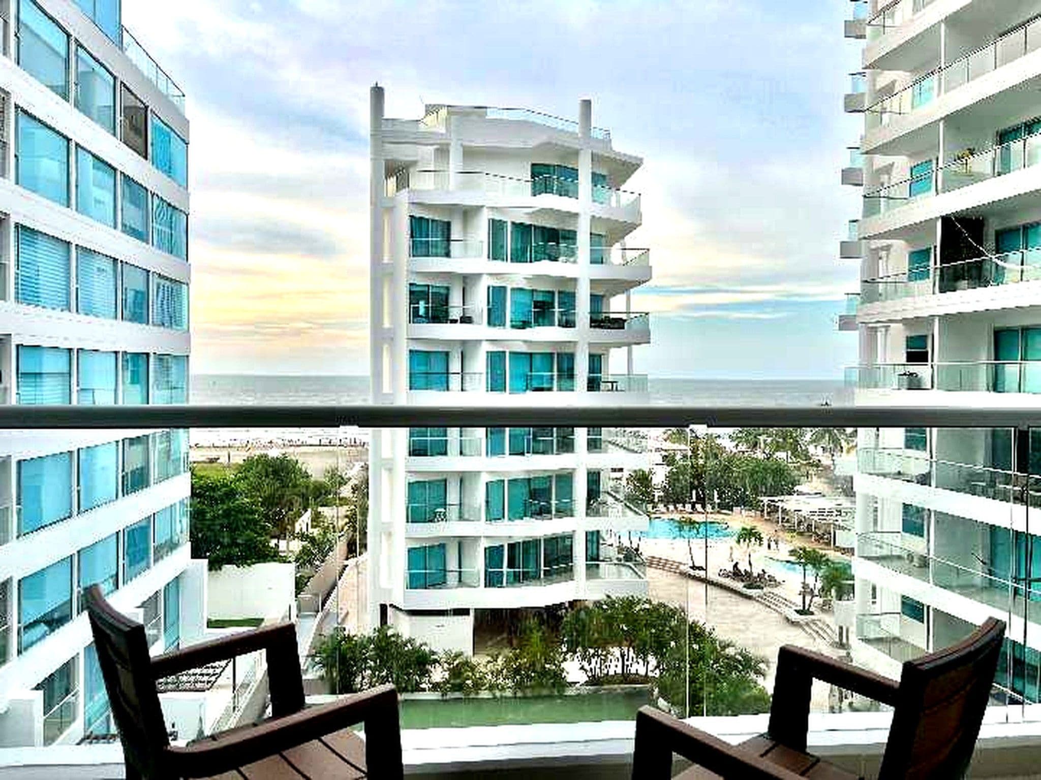 Um hotel moderno com várias varandas, área de piscina e vista para o oceano.
