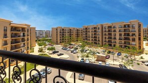 Um edifício residencial com várias varandas, área de estacionamento e céu azul.