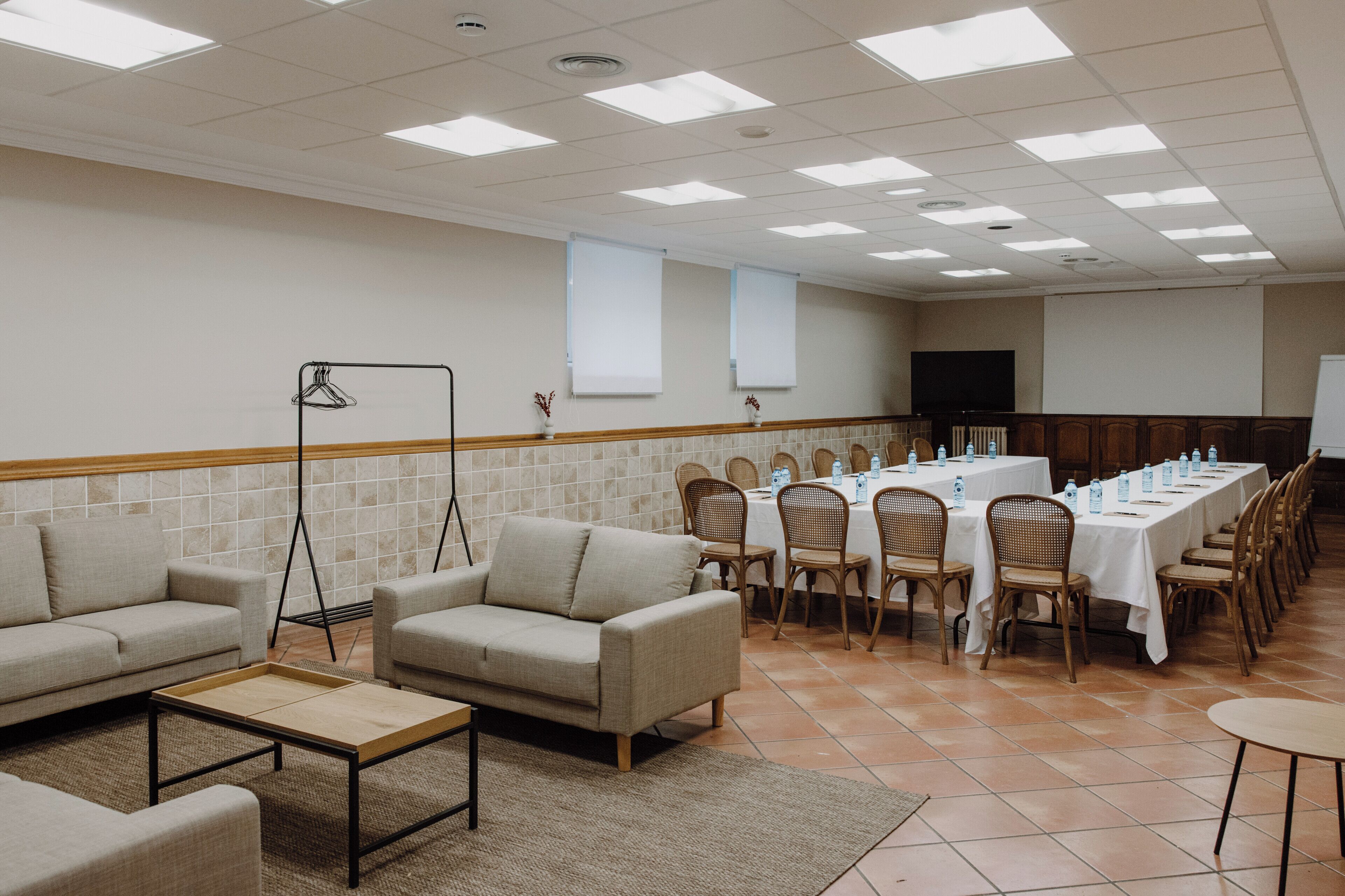 Uma sala de conferências com uma mesa comprida, cadeiras, sofás e piso coberto de carpete.