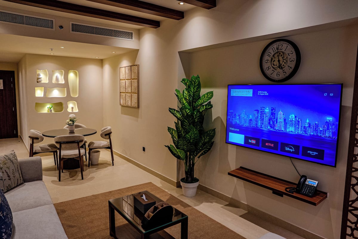 Uma sala de estar moderna com uma televisão de tela plana, um relógio e um vaso de planta.