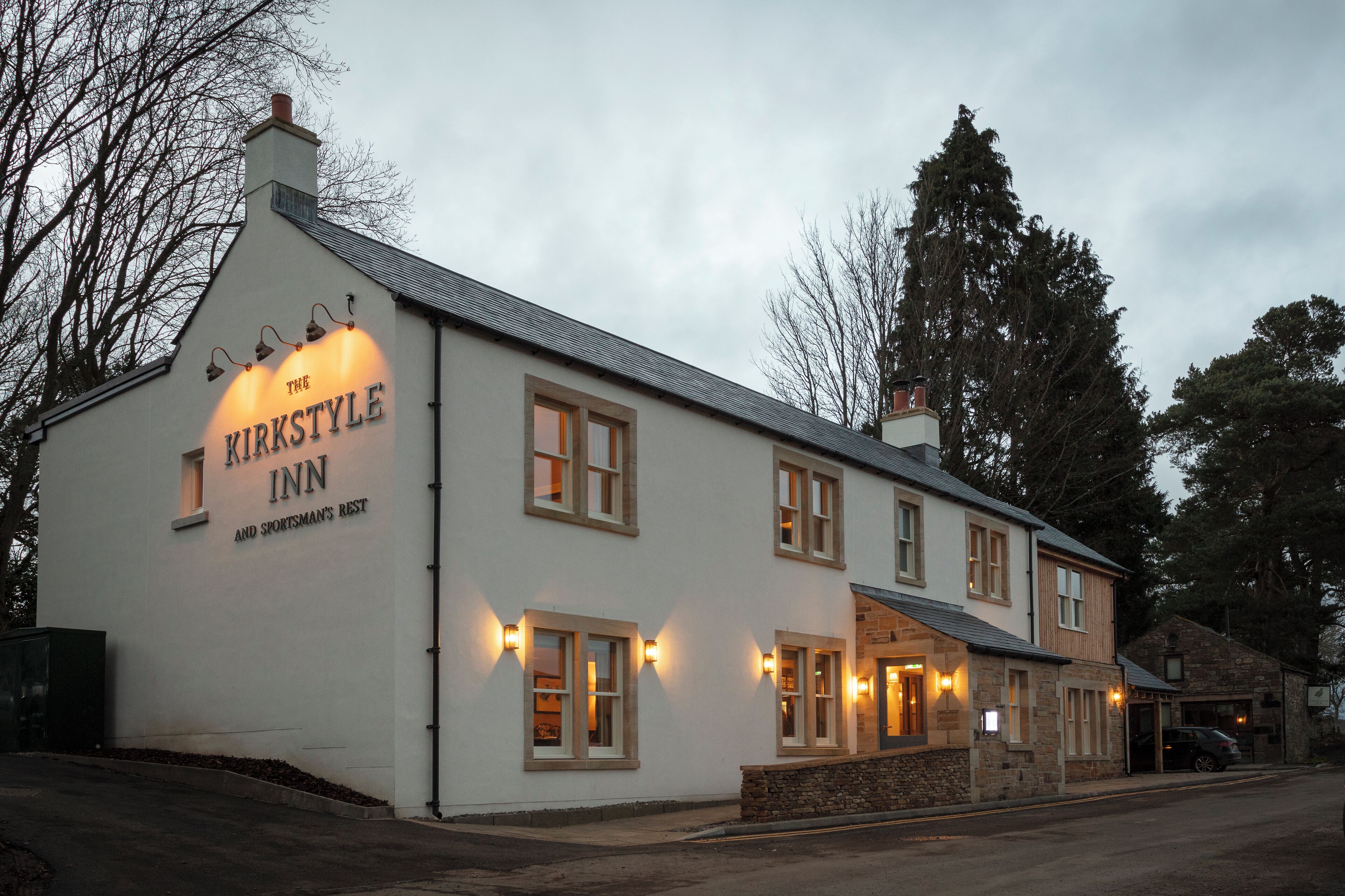 Um edifício branco com uma placa que diz 'The Kirkstyle Inn and Sportsman's Rest'.