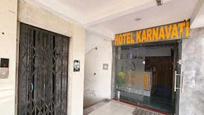 Entrada de hotel com um portão de metal e uma placa com a inscrição "HOTEL KARNAVATI".
