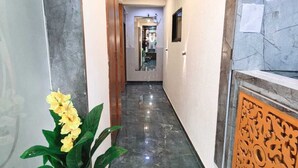 Uma área de recepção de hotel com piso de mármore, balcão de atendimento e um vaso de planta.
